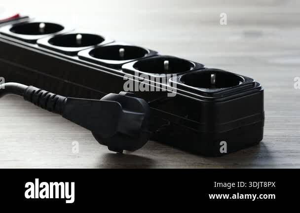 Woman putting plug into power strip at wooden table, closeup Stock ...