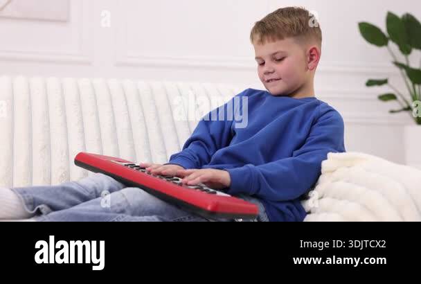 Cute little boy playing toy piano on sofa at home Stock Video Footage ...