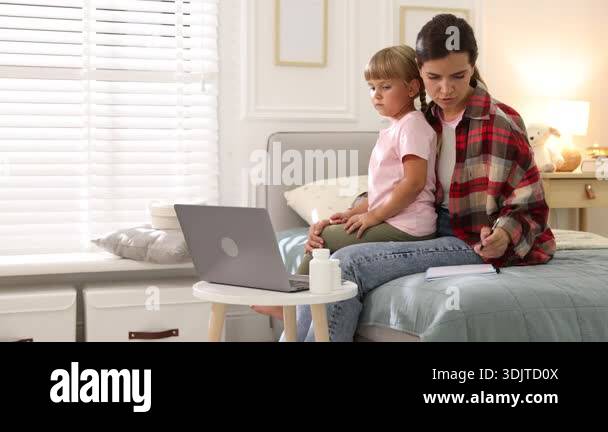 Telehealth. Mother taking notes during online consultation with doctor ...