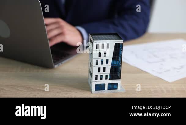 Real estate agent working with laptop and architectural drawing at ...