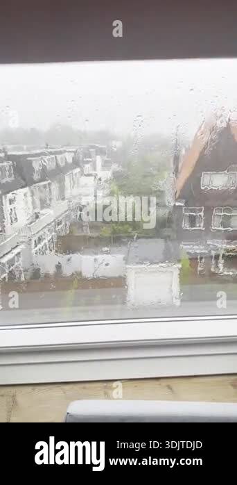View on buildings and trees through window with water droplets during ...
