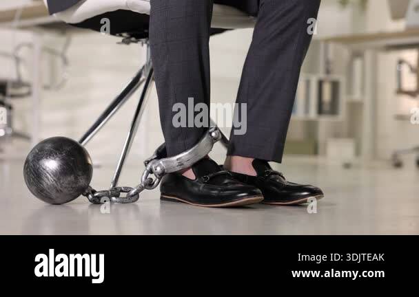 Businessman with metal ball and chain on his leg in office, closeup ...