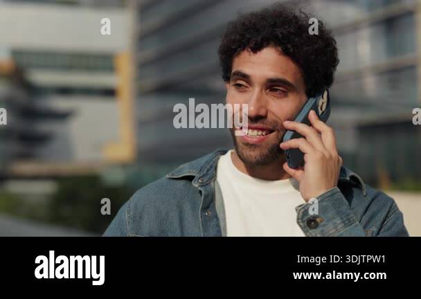 Portrait of bearded Hispanic man talks on smartphone standing against ...