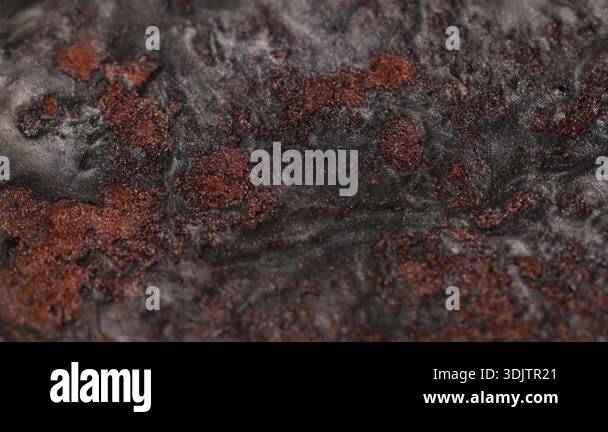 Viscous close-up of black steel paint bubbling and churning slowly ...