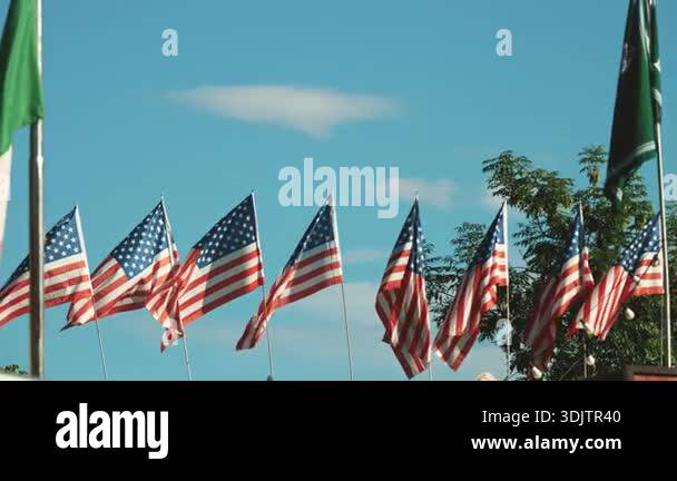 Multiple American flags waving in the wind against a clear blue sky ...