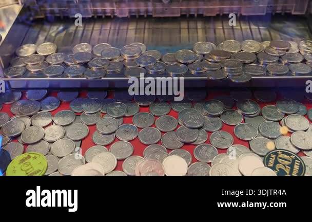 Close up of shiny coins inside a penny falls arcade machine at a night ...