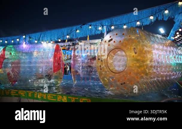 Children playing inside inflatable water rollers in an amusement park ...