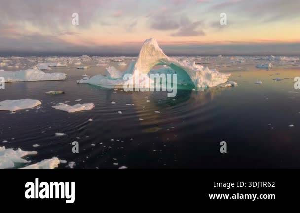 Large Arctic iceberg at sunset in Greenland with floating ice and calm ...