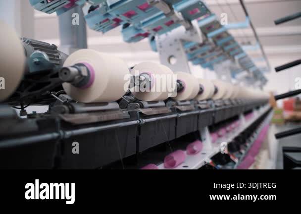 Rows of thread spools on a spinning rack inside a textile plant ...