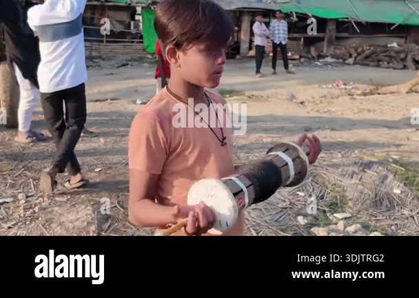 Indian boy holding a large kite string spool in urban outdoor setting ...