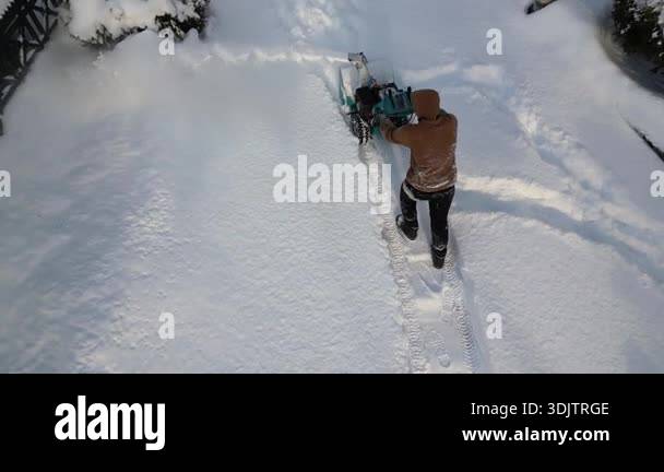 Man dressed in thermal winter clothing moves modern snow blower forward ...