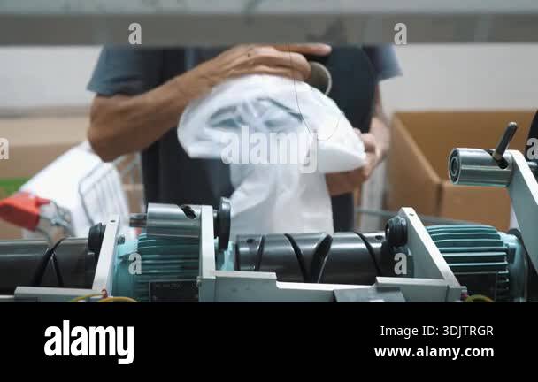 Professional factory worker packing spools of colorful yarn into ...