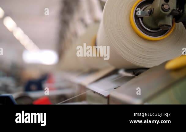 Close-up view of yarn spools spinning on textile equipment during ...