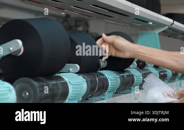 Close up of textile factory worker hands packing white yarn spools into ...