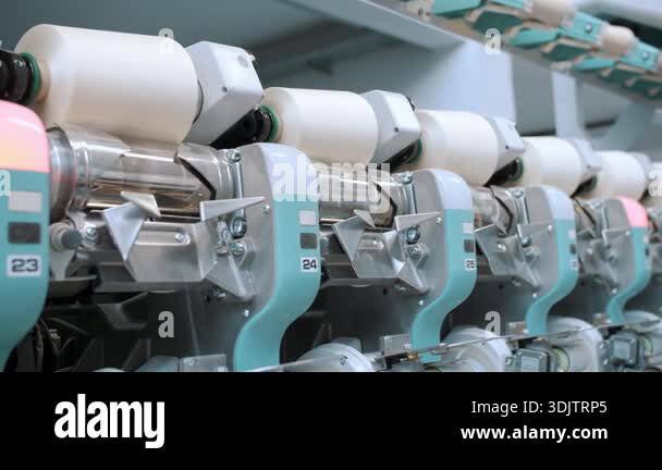 Interior view of a textile factory with operating spinning machinery ...