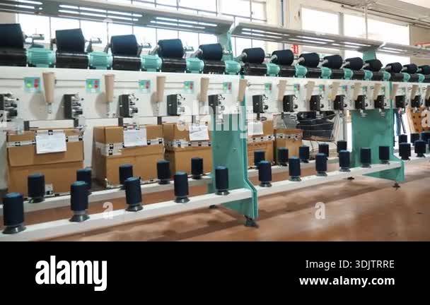 Automated textile machinery rewinding cotton threads onto spools in a ...