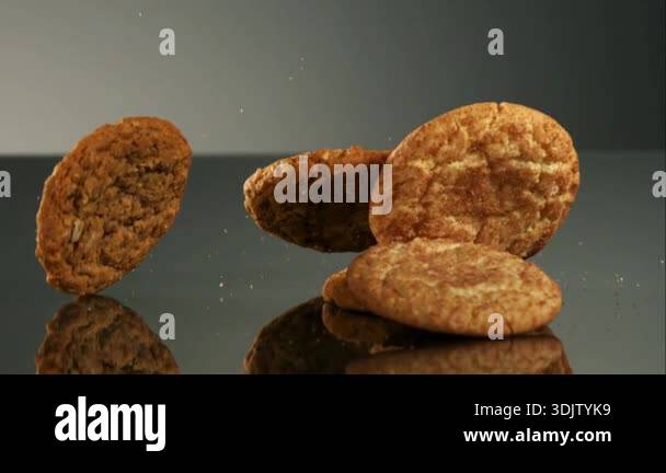 Various golden brown cookies falling and piling up on a dark mirror ...