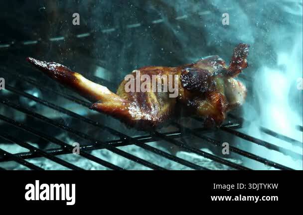 A succulent seasoned roasted chicken wing sits on a black metal grill ...