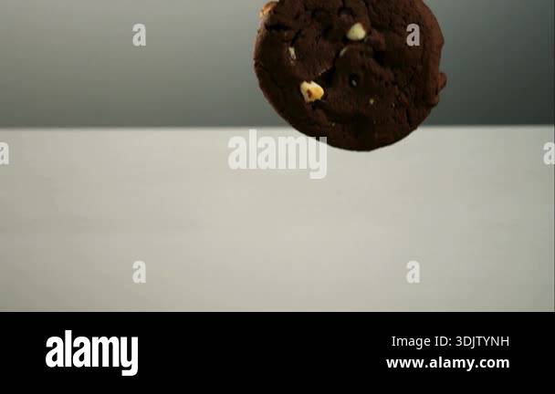 Dark chocolate cookies with white chips falling and bouncing on a white ...