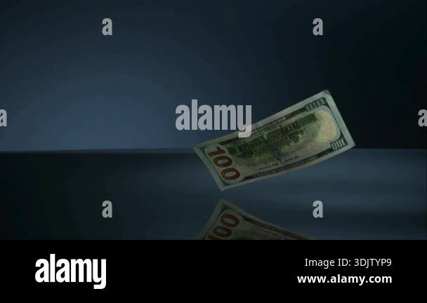 Slow motion shot of one hundred dollar bills falling down on a dark ...