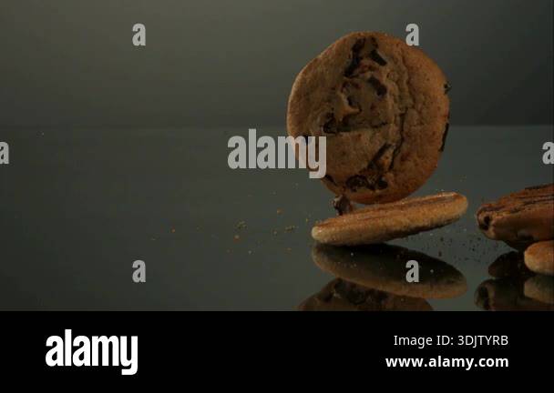 Multiple chocolate chip cookies falling down and stacking on a dark ...