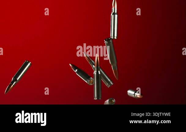 Many metallic rifle bullets and cartridges falling down in front of a ...