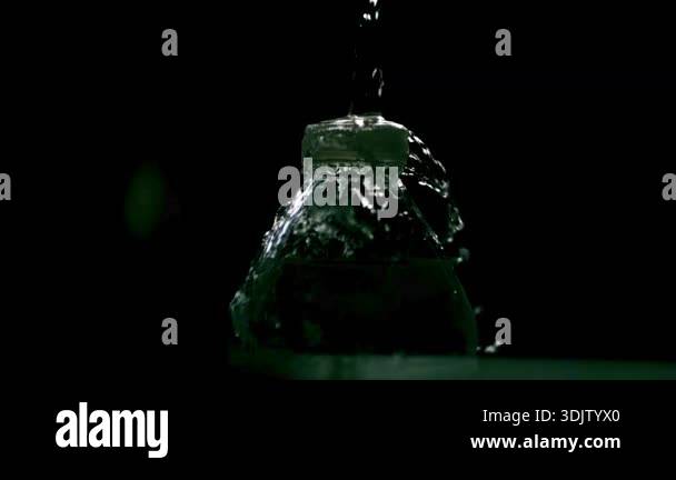 Stream of fresh water pouring over the closed cap of a plastic bottle ...