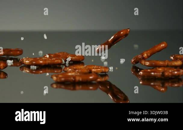 Salted pretzel twists and sticks falling and bouncing on a dark ...