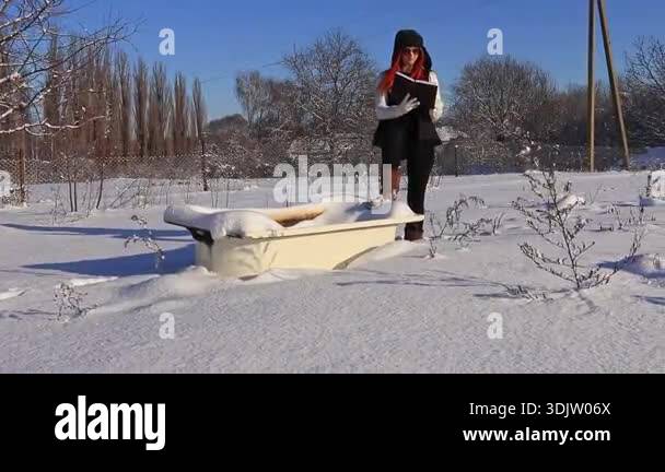 A beautiful girl with a diary in her hands near an old bathtub in the ...