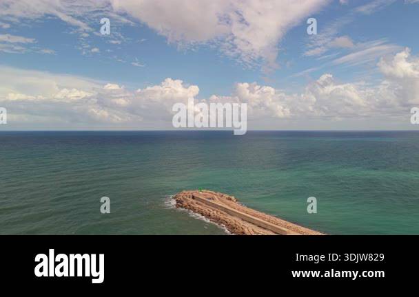 Aerial view of Denia breakwater with green lighthouse stretching into ...