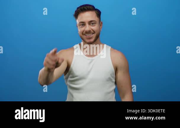 Young man with a beard smiling and pointing at the camera against an ...