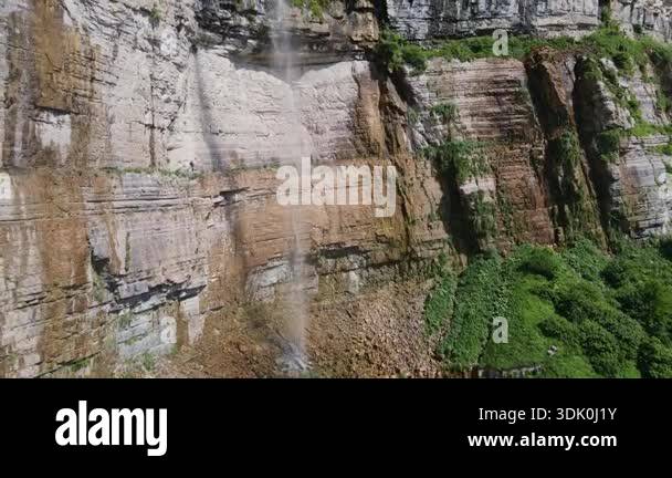Aerial drone view shows a narrow waterfall on tiered limestone cliffs ...