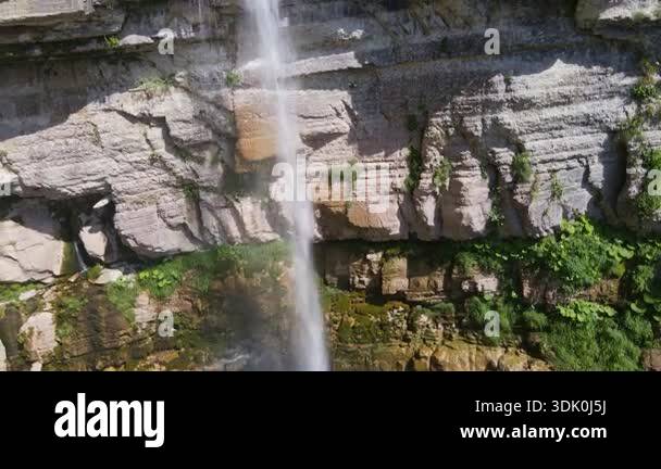 Aerial view shows a narrow vertical waterfall on a layered limestone ...