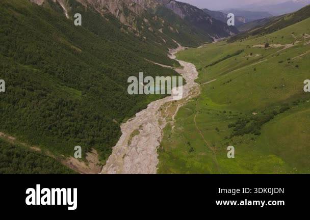 Aerial view shows a braided river, a turquoise alpine pond, and stone ...