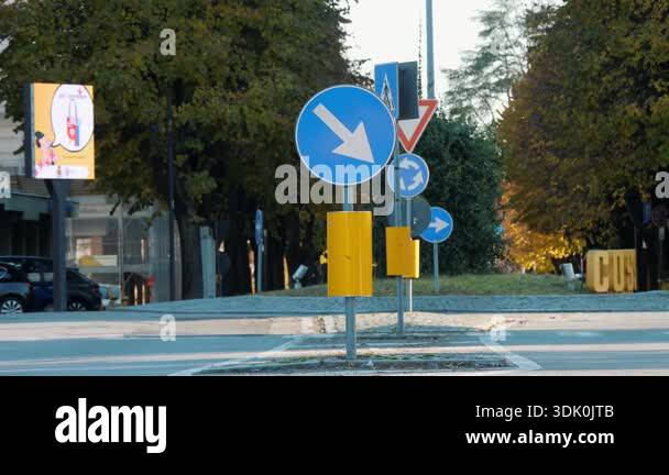Group of traffic signs standing before a city roundabout in Italy under ...