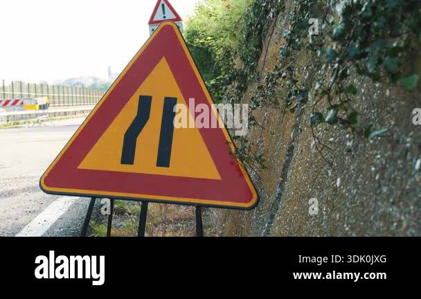 Road sign narrowing of the road in a triangular shape close-up. Red and ...