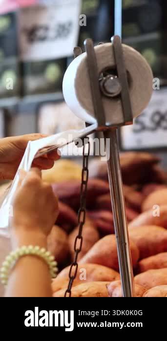 A person pulls a plastic bag from a dispenser in a market setting ...