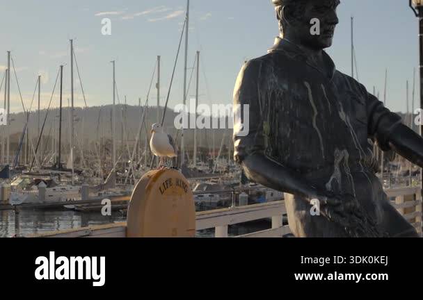Statue of a fisherman holding a net on a pier in Monterey California on ...