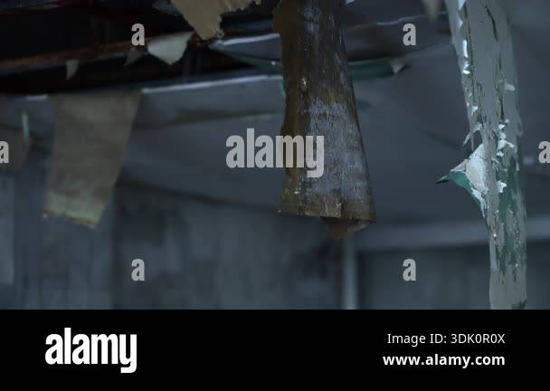 Water drips from peeling ceiling panels inside a dark, empty underpass ...