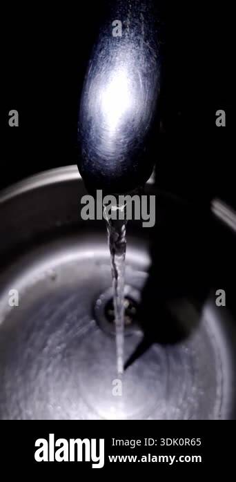 Water flows from a metal faucet into a stainless steel sink. Dramatic ...