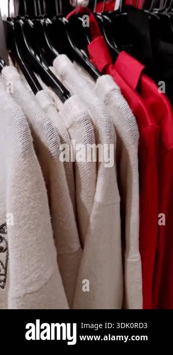 Womens knit sweaters and red satin shirts hang on a rack in a clothing ...