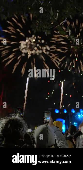 Intense colorful fireworks burst over night crowd creating energetic ...