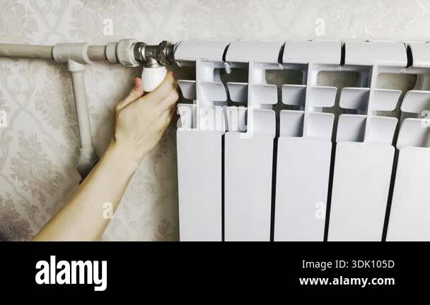 hand adjusting white radiator valve ornate floral wallpaper background ...
