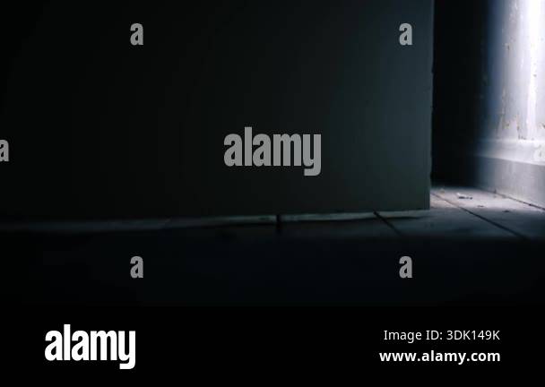 Person leaving dark room through door close up zoom shot selective ...