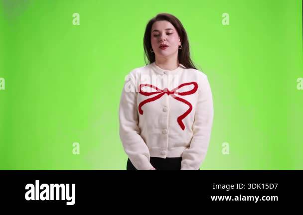 Young woman with disappointed expression and clasped hands on green ...