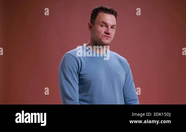 Man with tense serious expression standing on brown studio background ...