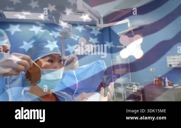 Surgeon receiving blue cap from assistant and fitting mask under flag ...
