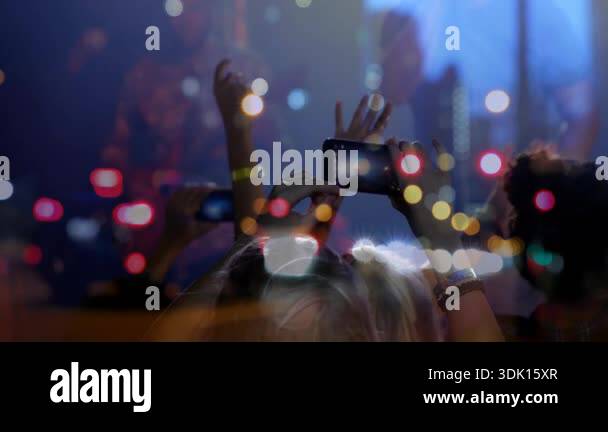 Concertgoer raising smartphone, capturing music show as crowd clapping ...
