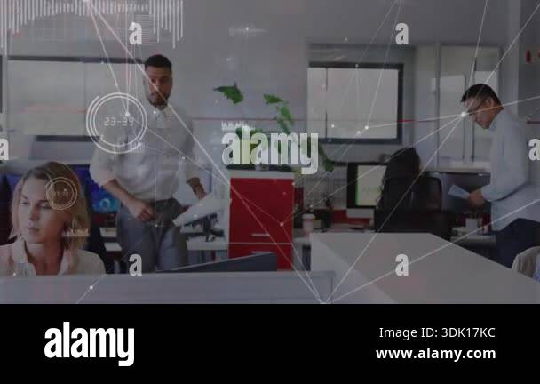 Male colleague walking to desk pointing to screen reviewing business ...