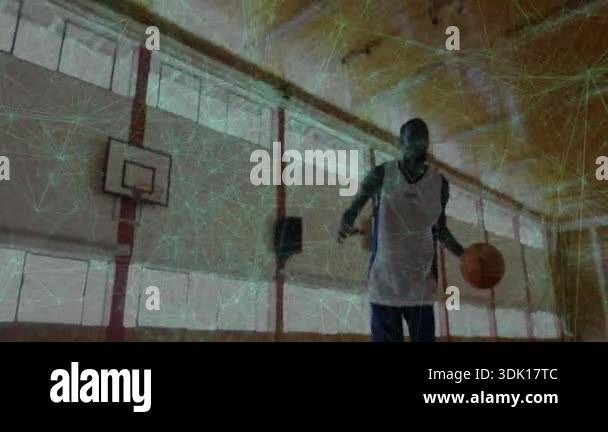 Basketball player entering gym dribbling toward hoop then shooting ball ...
